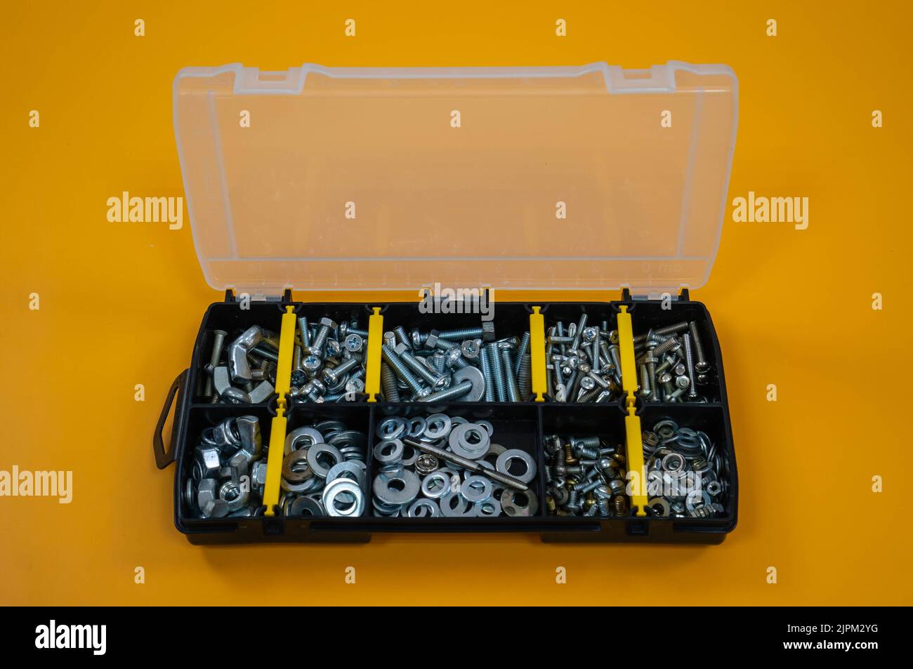Case organizer with screws, nuts and washers on a yellow background ...