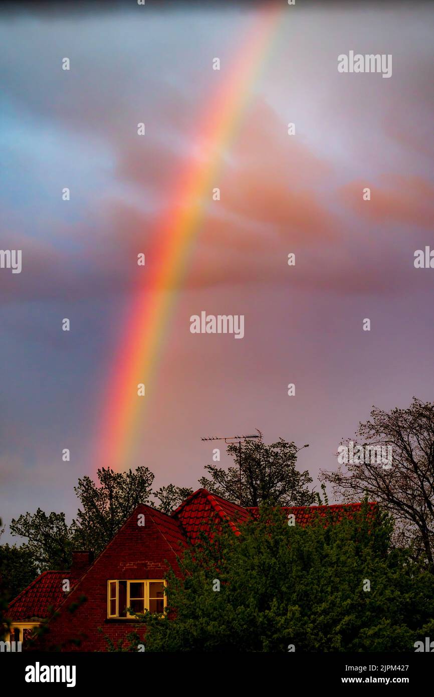 A vertical shot of a rainbow behind a country house Stock Photo - Alamy