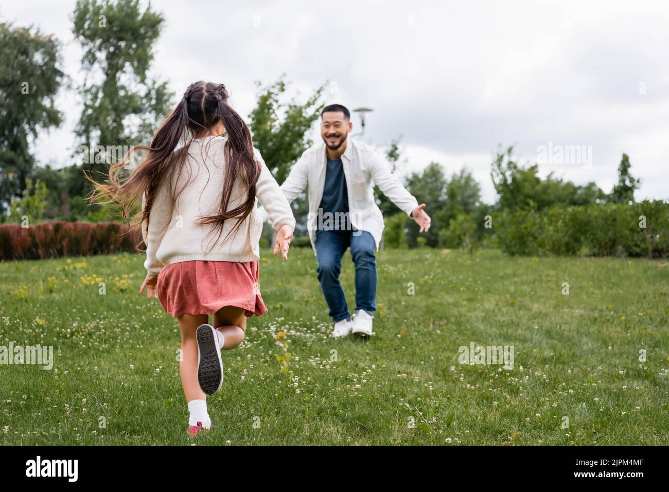Preteen girl running to asian dad in summer park Stock Photo - Alamy