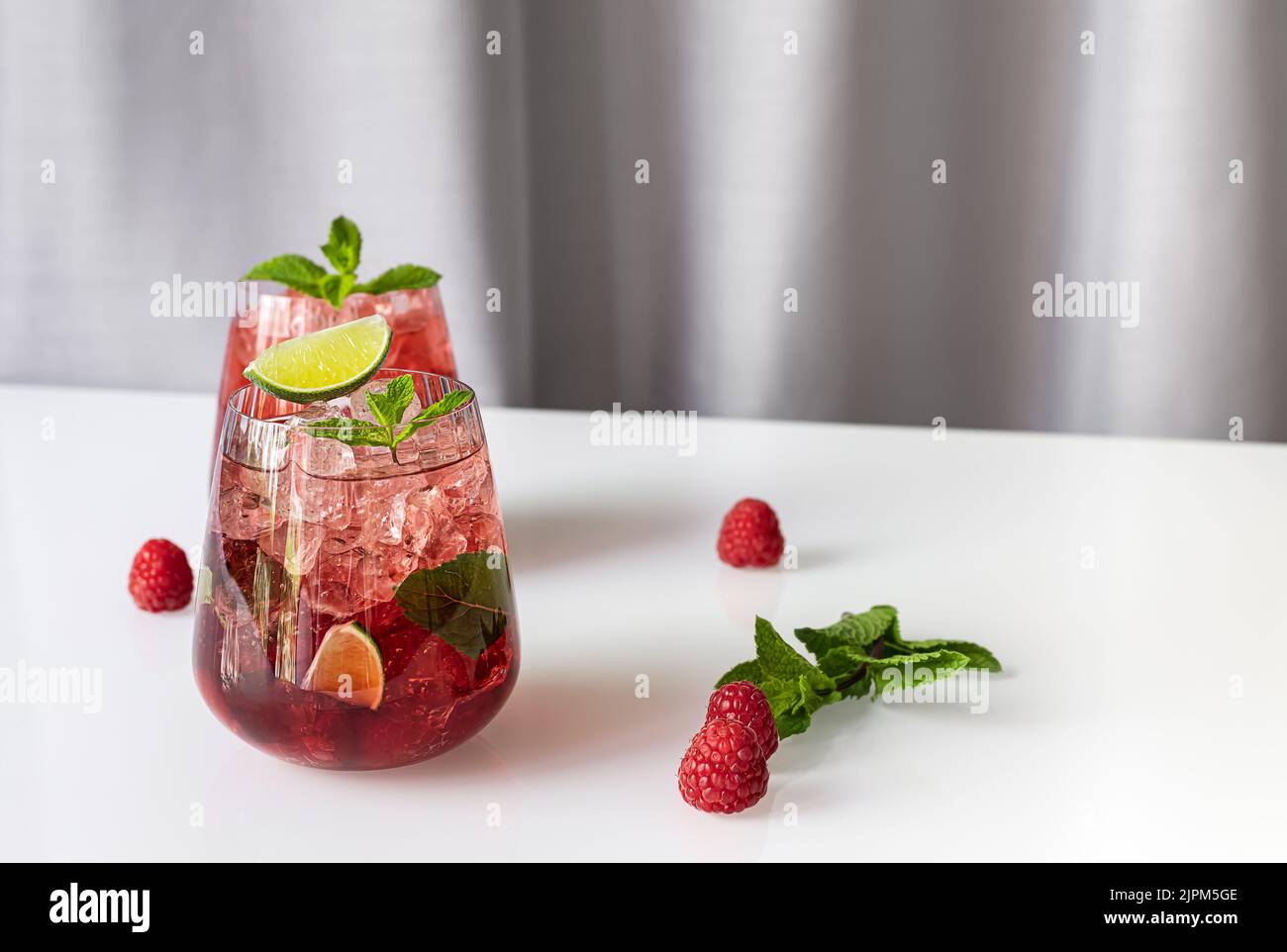 Fresh summer lemonade with raspberry, lime, soda water, and ice in ...
