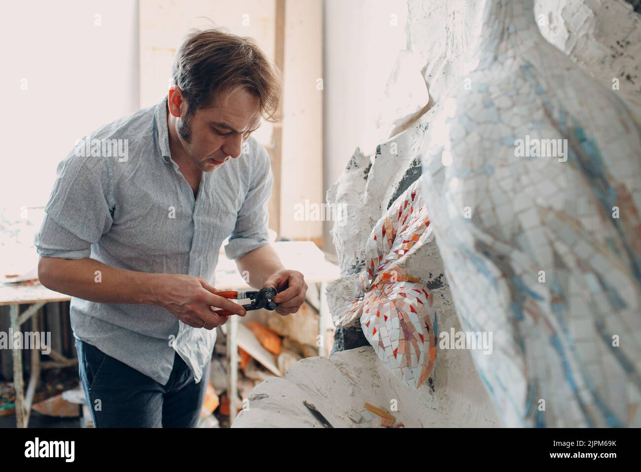 Workplace mosaics master making smalt glass mosaic panel. Man mosaicist ...