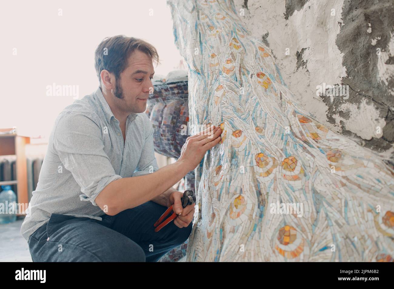 Workplace mosaics master making smalt glass mosaic panel. Man mosaicist ...