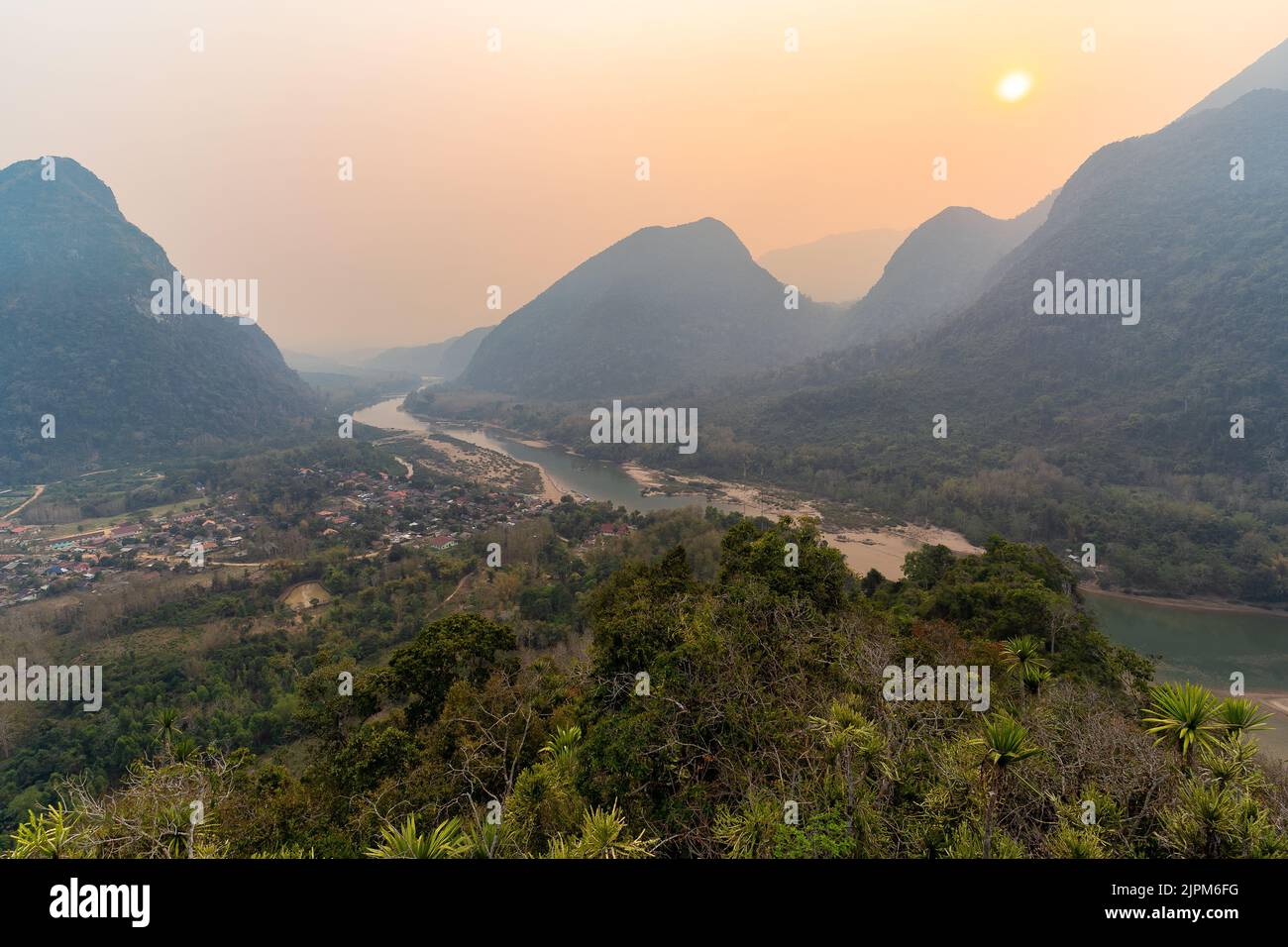 An aerial view of Muang Ngoy village in green mountains near a river at ...