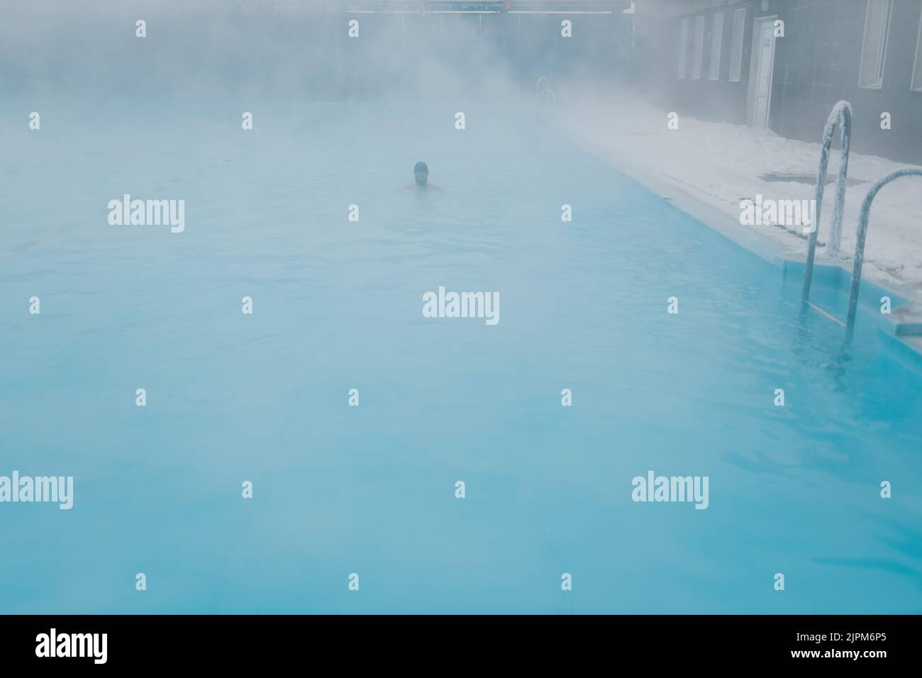 Fit swimmer male training swim in open winter swimming pool with fog ...
