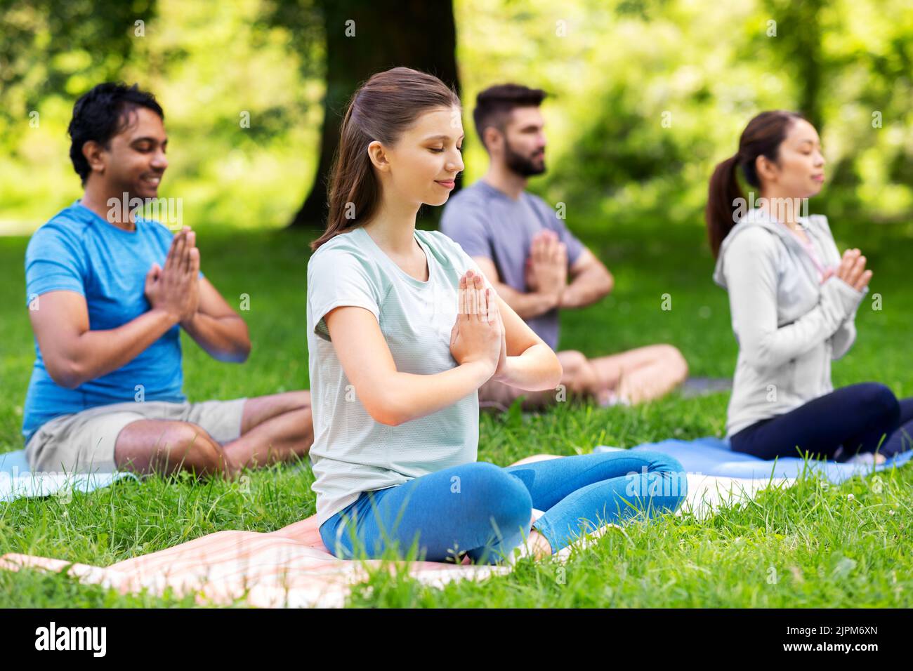 group of happy people doing yoga at summer park Stock Photo - Alamy