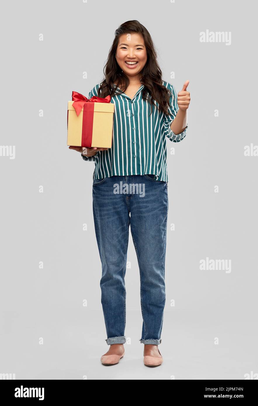 happy asian woman with gift box showing thumbs up Stock Photo - Alamy