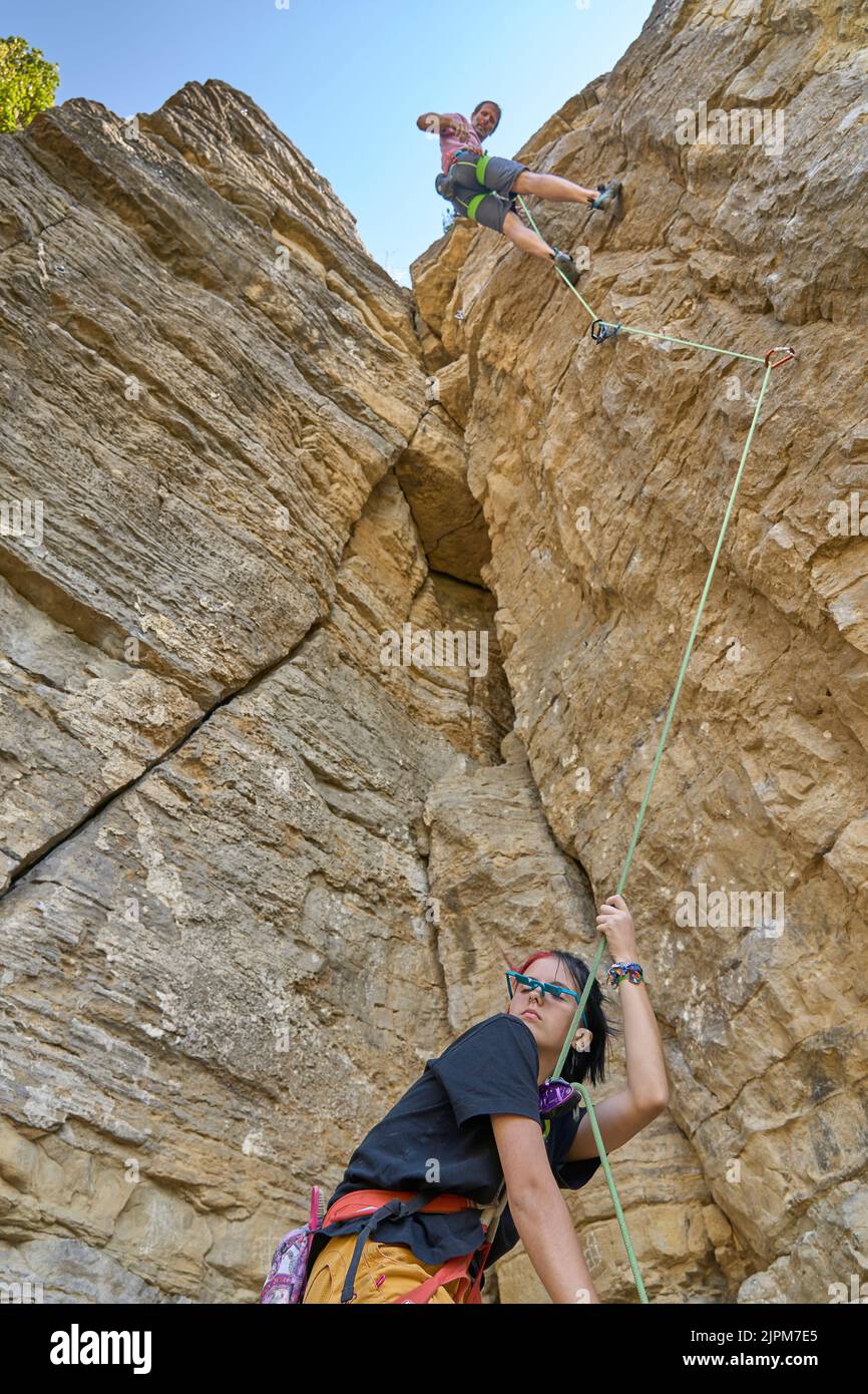 Teenage girl securing her climbing partner by a securing rope system ...