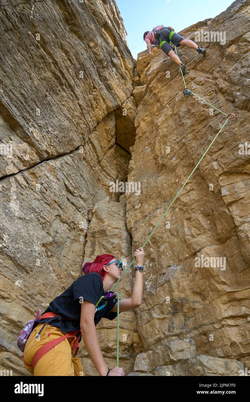 Teenage girl securing her climbing partner by a securing rope system ...