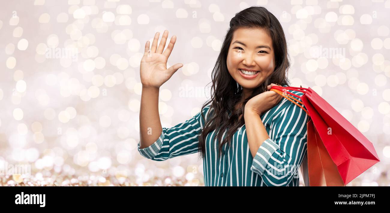 happy asian woman with shopping bags waving hand Stock Photo - Alamy