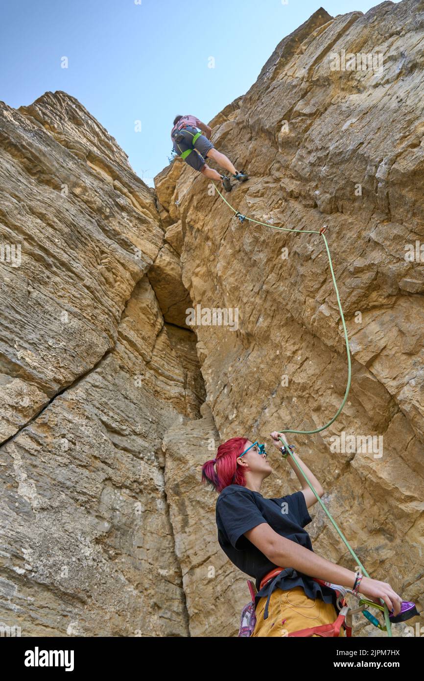 Teenage girl securing her climbing partner by a securing rope system ...