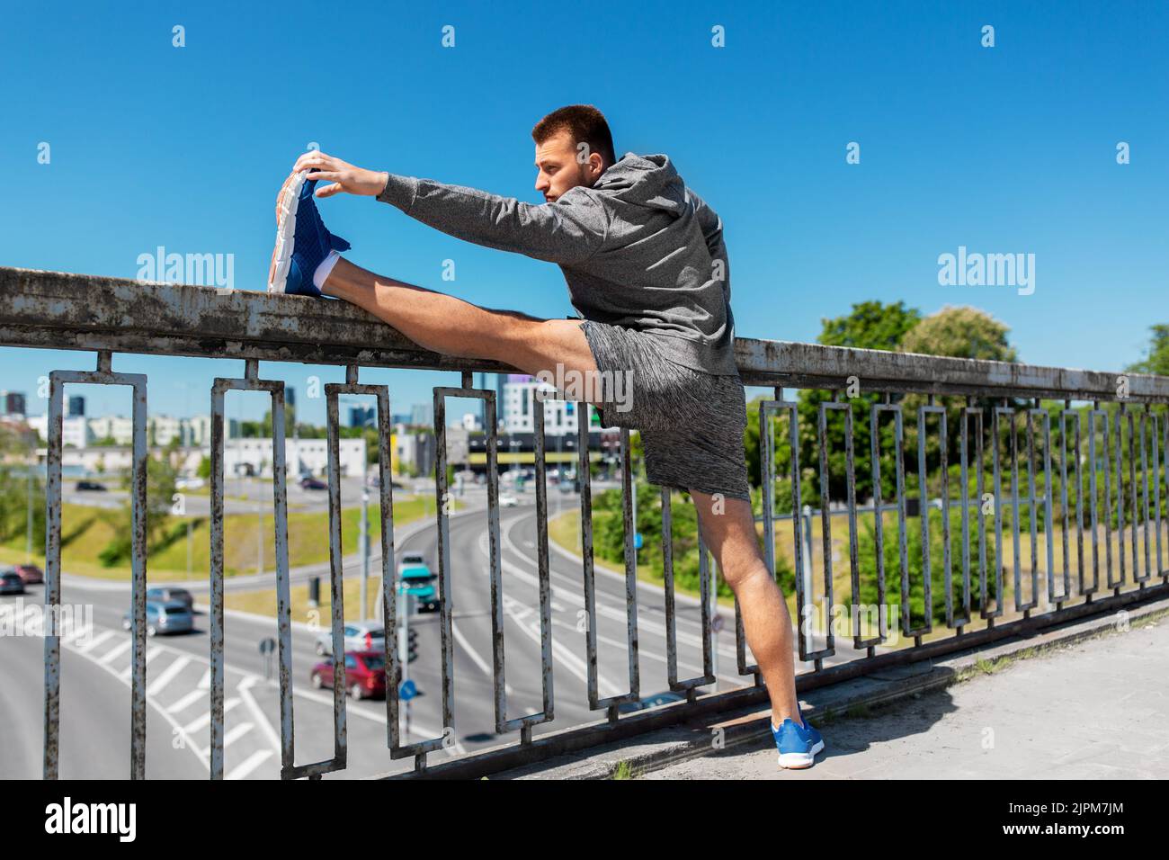 man stretching leg on bridge Stock Photo - Alamy