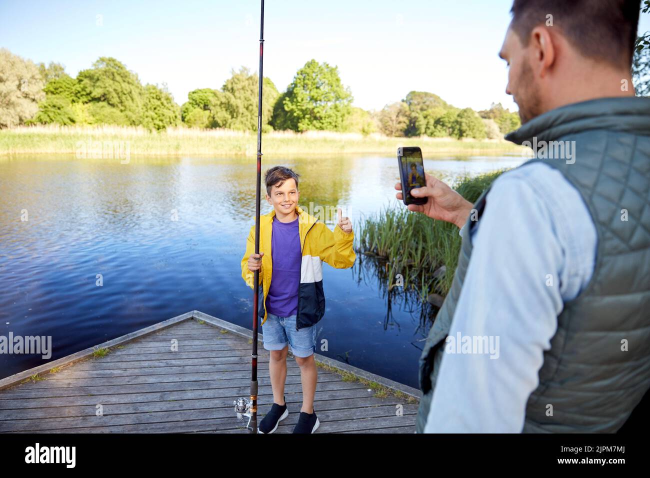 father photographing son with fishing rod on river Stock Photo - Alamy