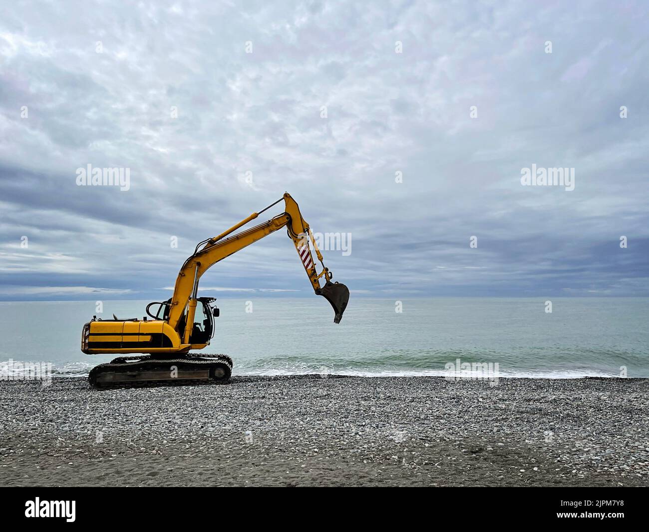 Excavator working on earthmoving at open pit mining on sea and sky ...