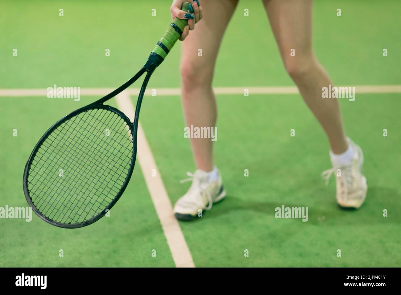 Tennis woman player legs playing training with racket and ball at court ...