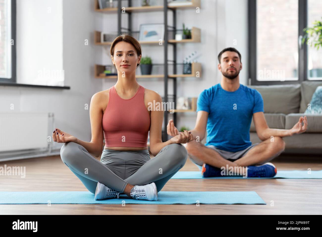 couple meditating in yoga lotus pose at home Stock Photo - Alamy