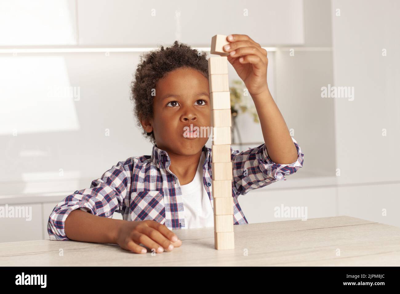 Cute clever child small boy playing and building a tower of wooden ...