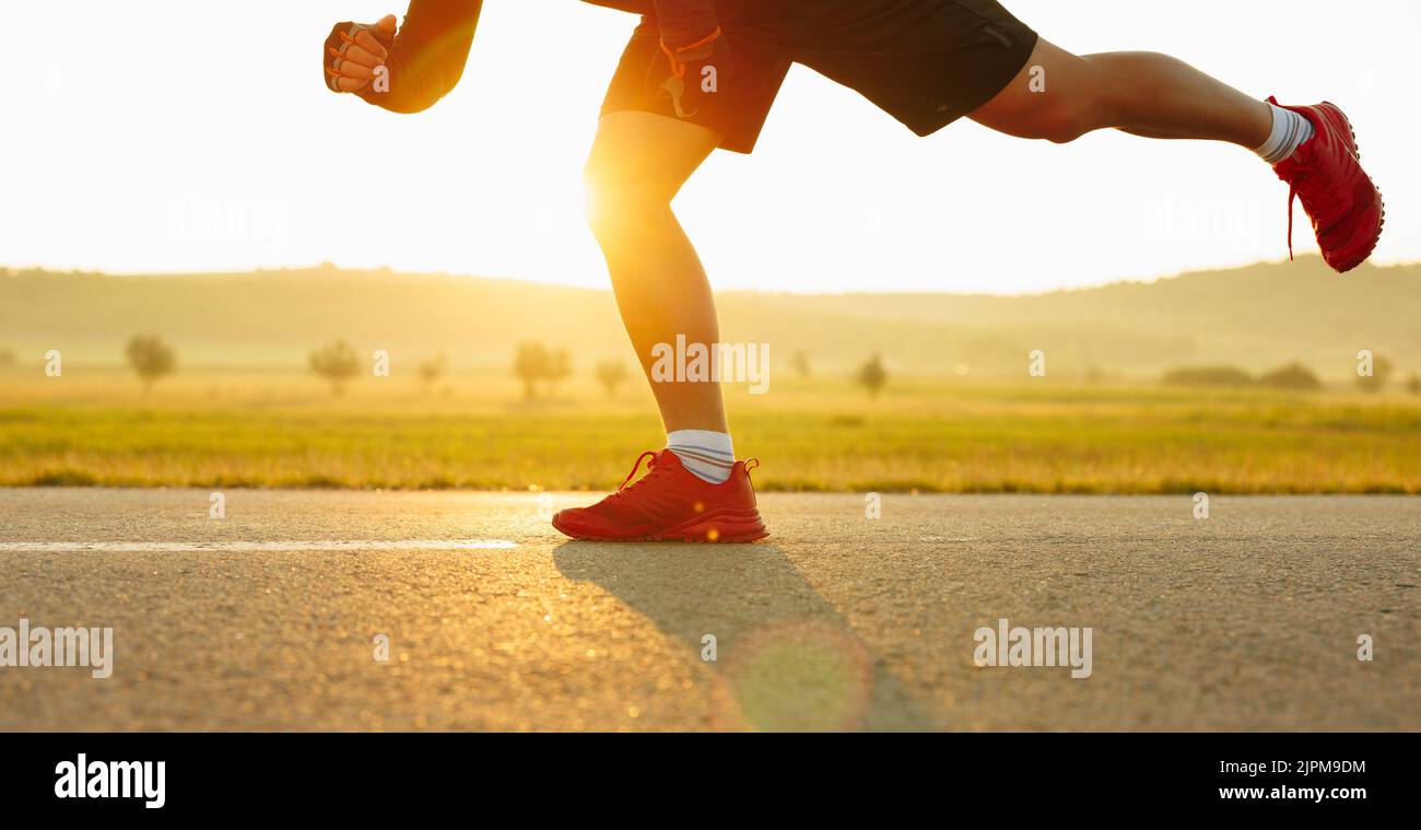 Sprinting man runner sprinter athlete running shoes and legs on track ...