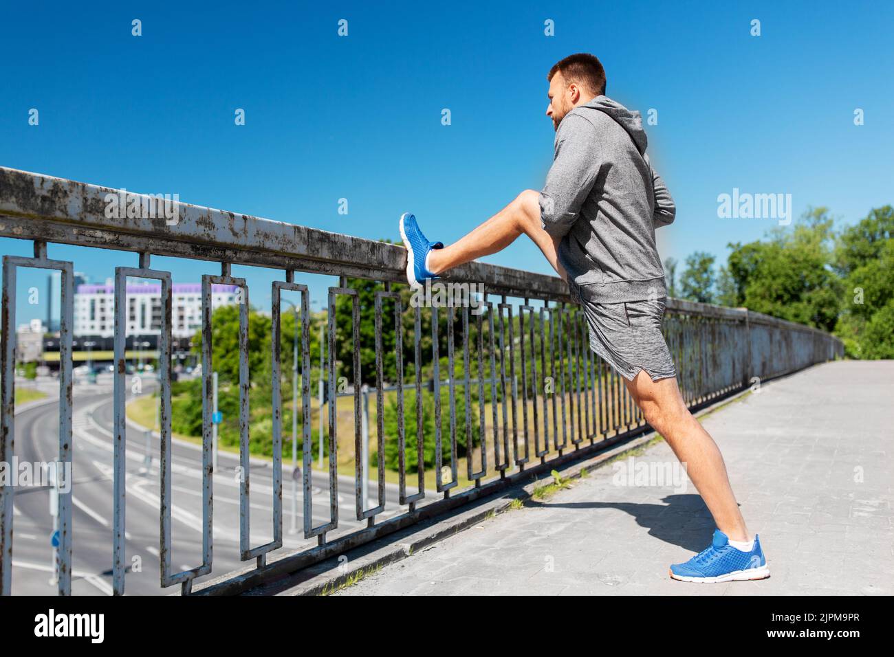 man stretching leg on bridge Stock Photo - Alamy