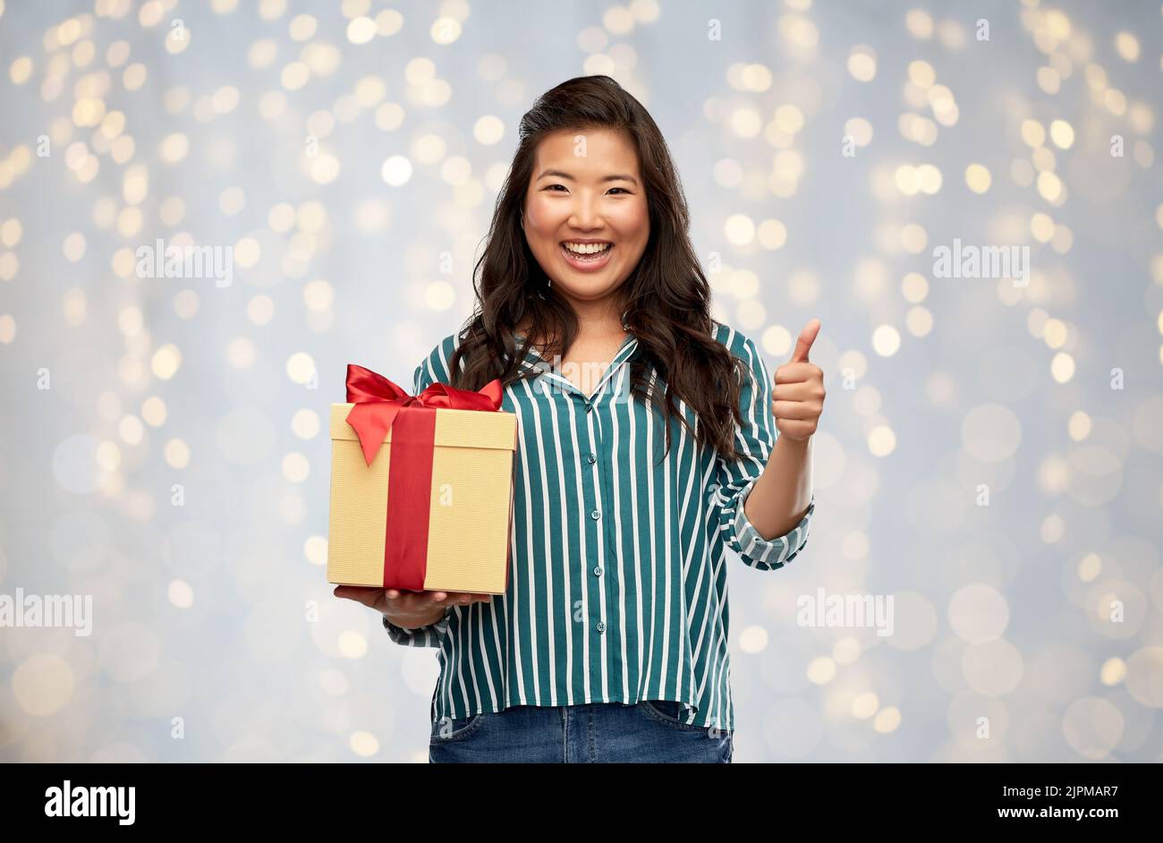 happy asian woman with gift box showing thumbs up Stock Photo - Alamy