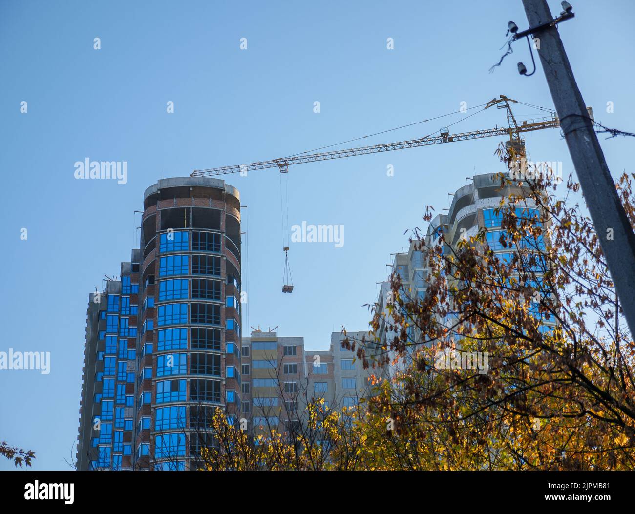 A crane lifts a load to the new buildings at the construction site, a ...
