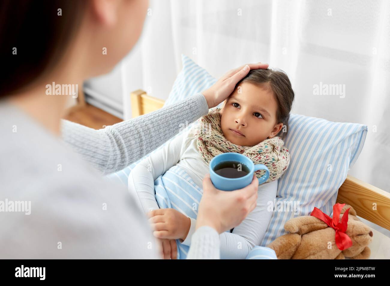 mother giving tea to sick daughter lying in bed Stock Photo - Alamy