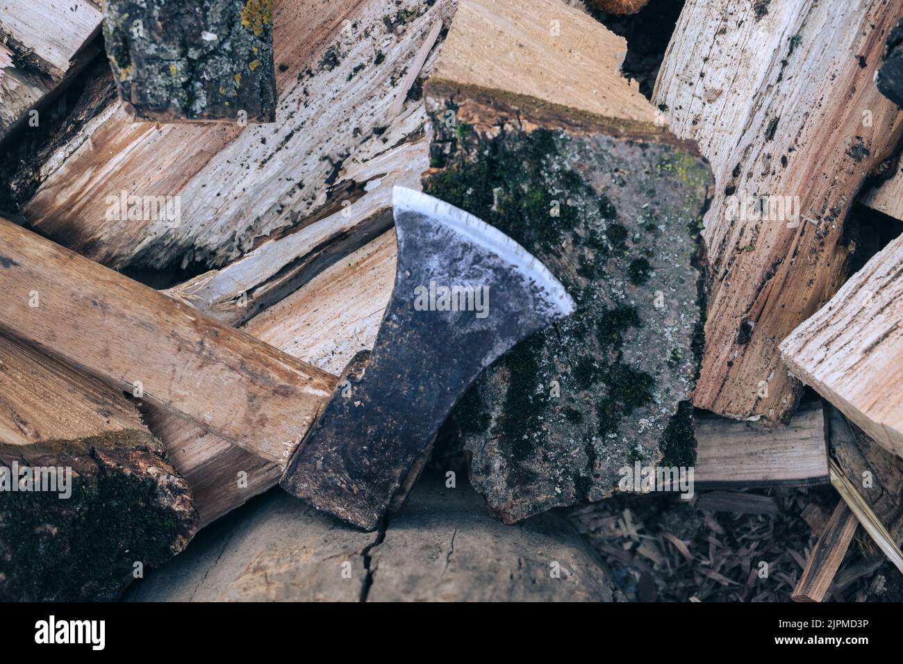 An old axe with a wooden handle lies on a stack of firewood, top view ...