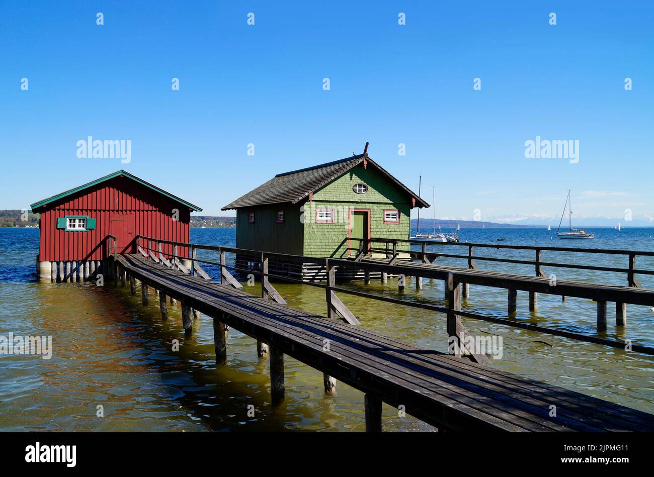a long wooden pier leading to the colorful boat houses on lake Ammersee ...