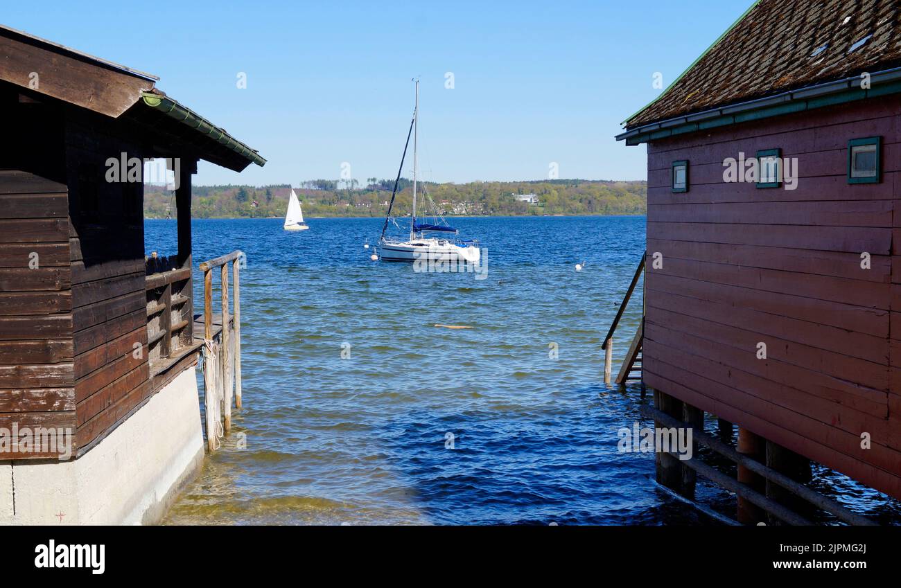 colorful boat houses on lake Ammersee with sailing boats and the Alps ...