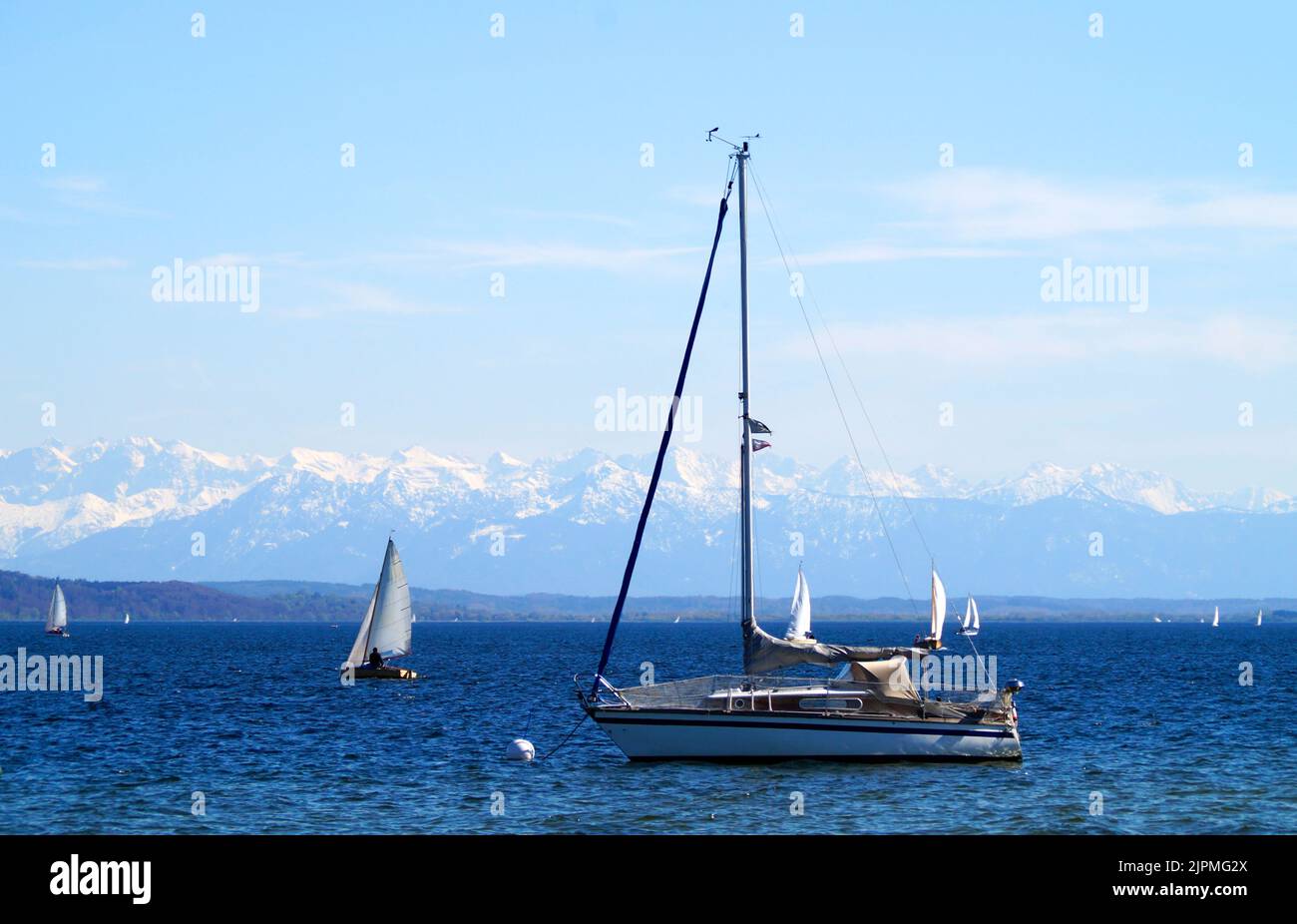 beautiful sailing boats on scenic and vast lake Ammersee with the snowy ...