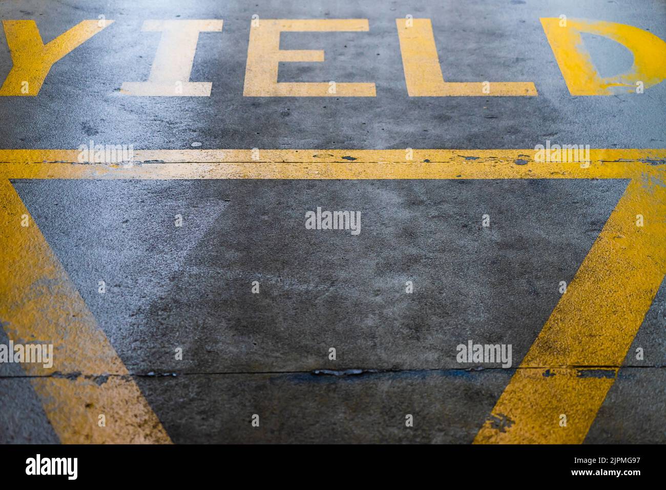 Worn yellow yield sign at the exit of a car park near Tallaght Square ...