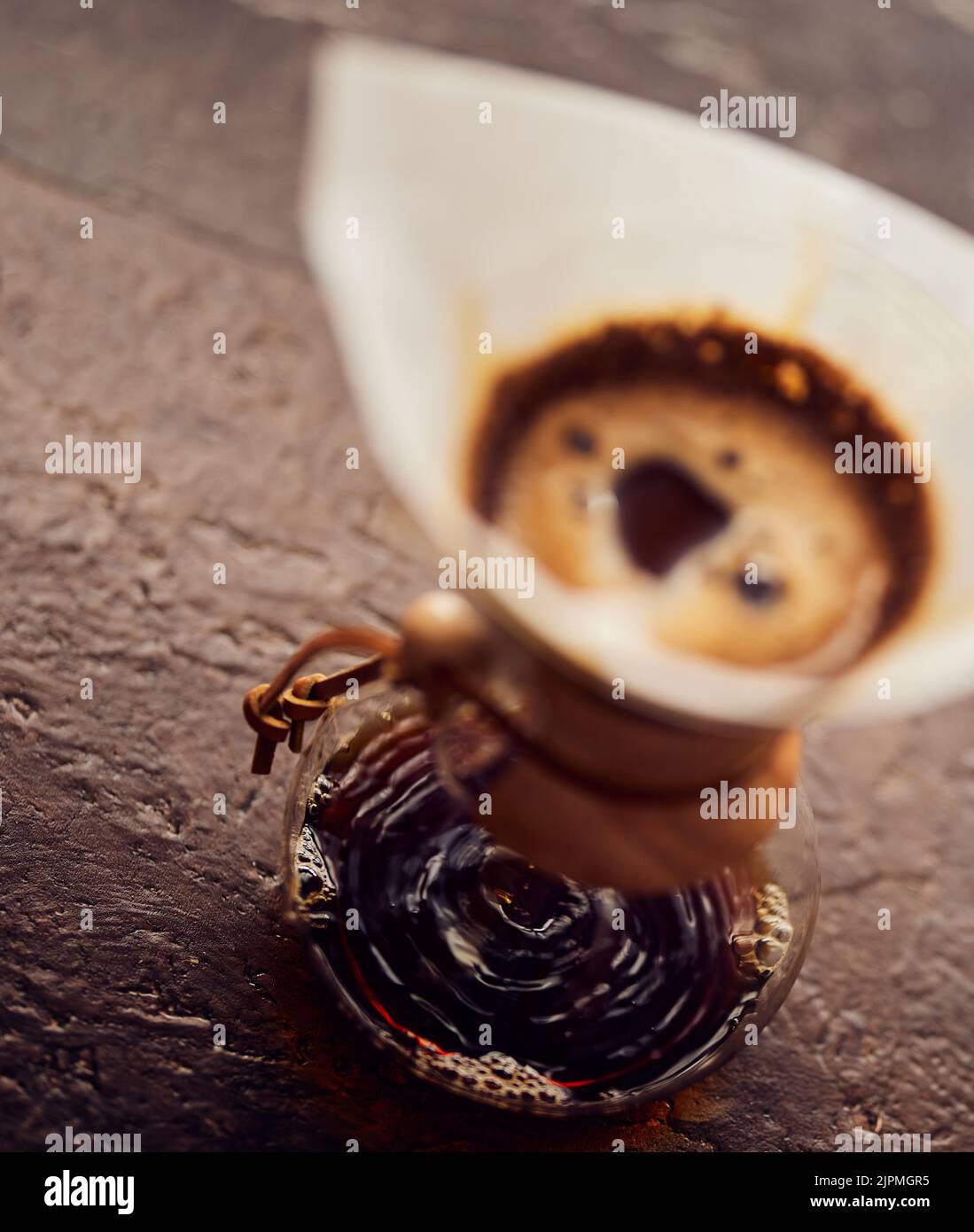 A vertical shot of boiling coffee in a blurred coffee brew with bubbles ...