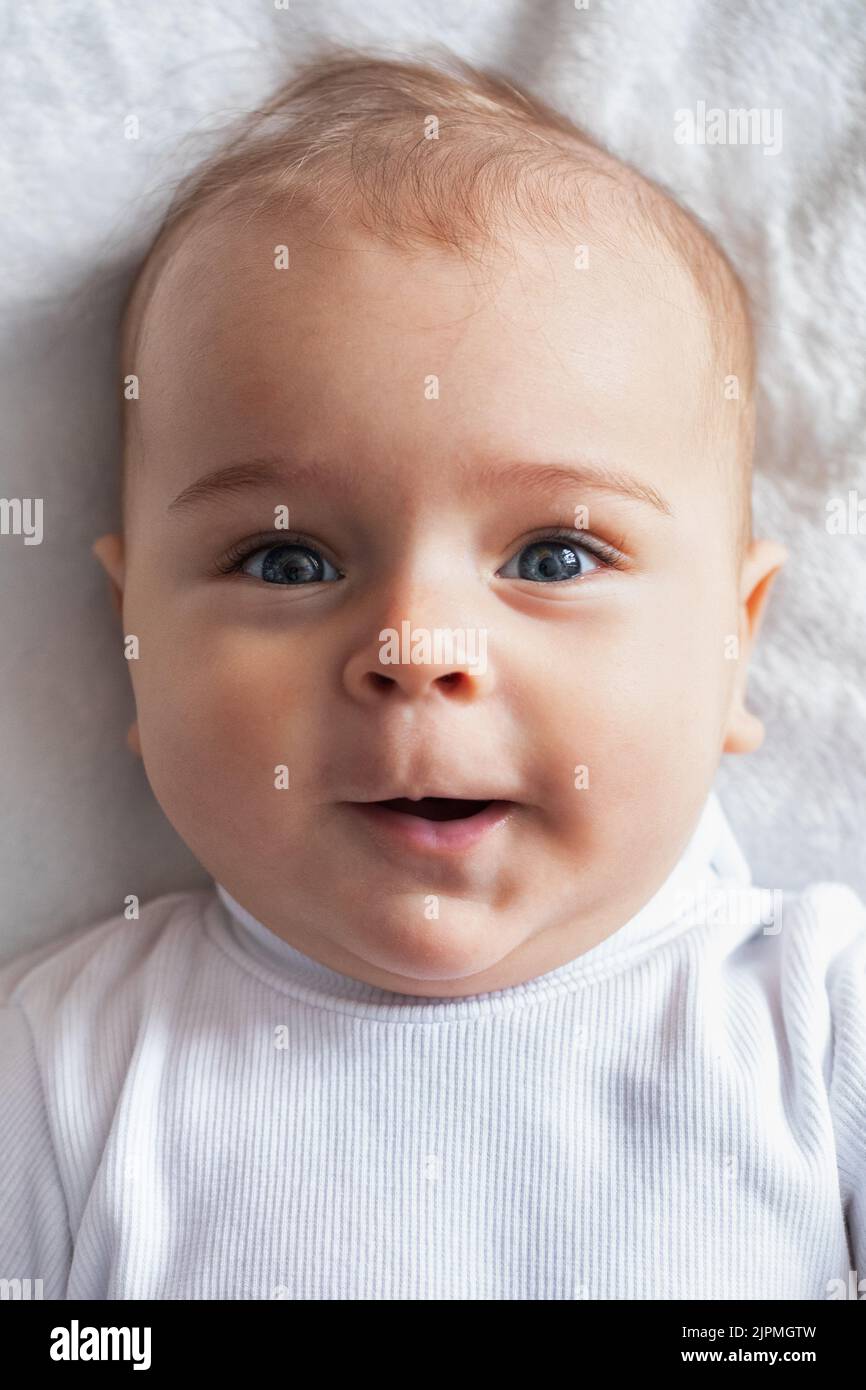 A cheerful little boy, a baby, lies on a white blanket. Close-up Stock ...