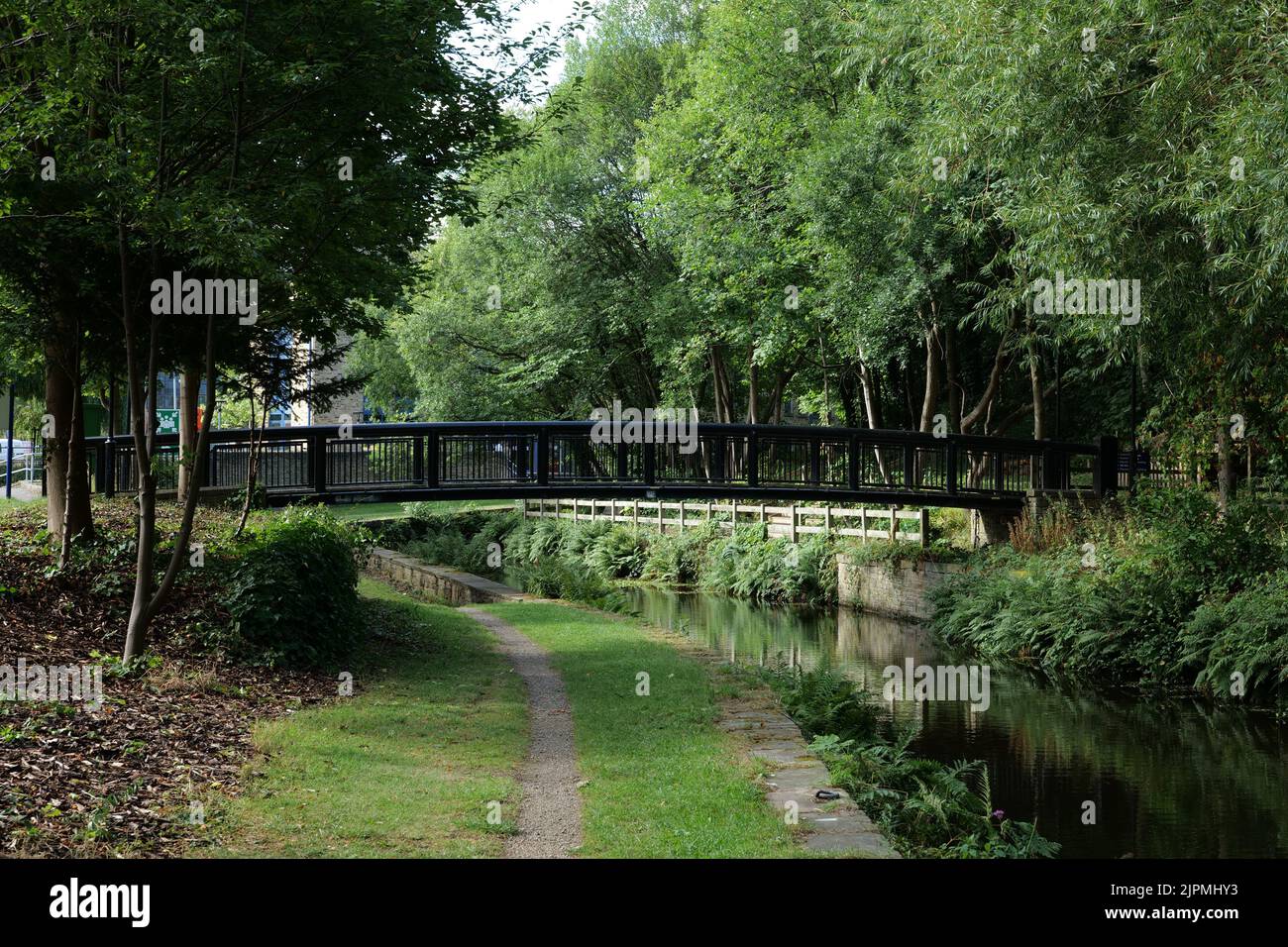 Arched black metal foot bridge over canal grass towpath and trees Stock ...