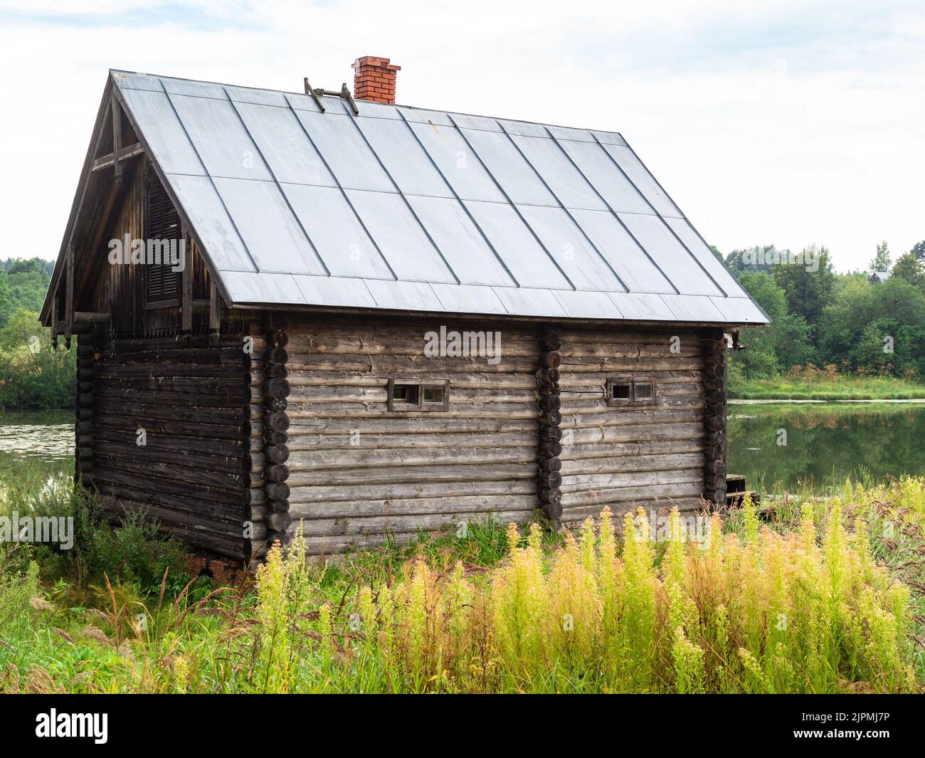 old log cabin on overgrown riverbank on summer day Stock Photo - Alamy