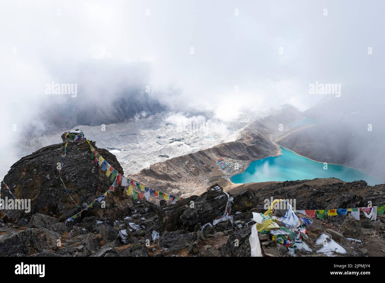 A view of beautiful prayer flags and a small, turquoise lake in the ...