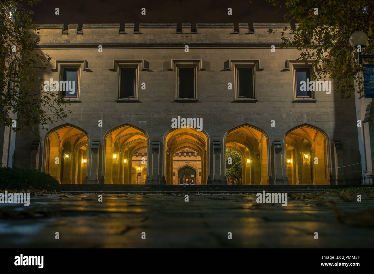The facade of the University of Melbourne with lights on during the ...