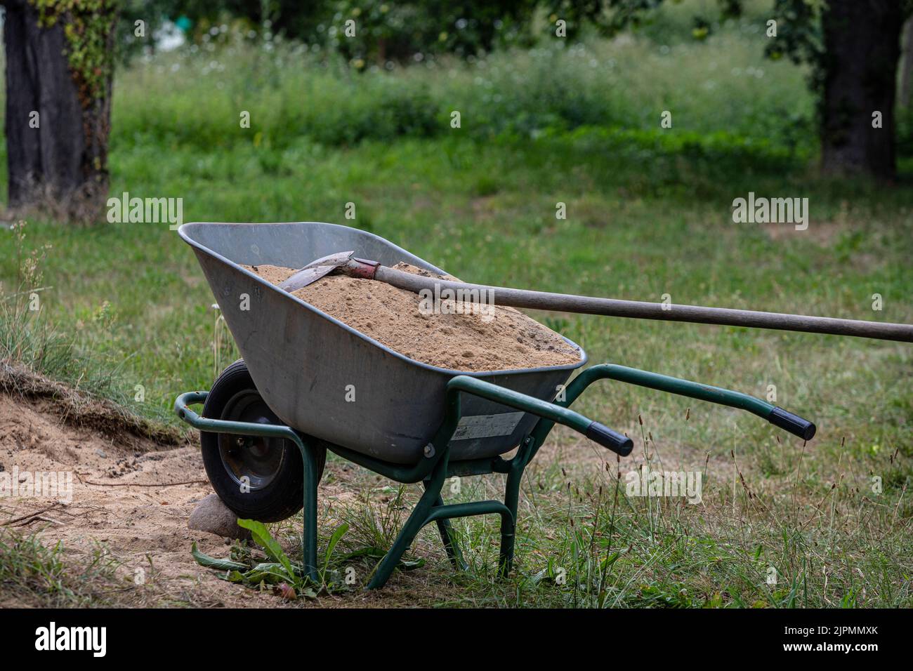 wheelbarrow with sand and shovel Stock Photo - Alamy