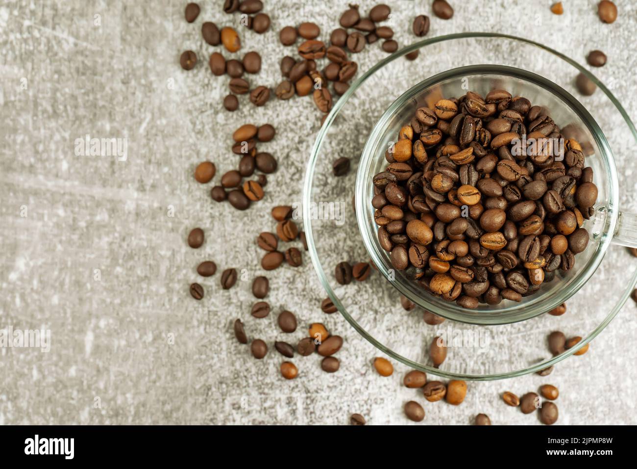 Transparent cup of coffee with coffee beans on gray concrete background ...