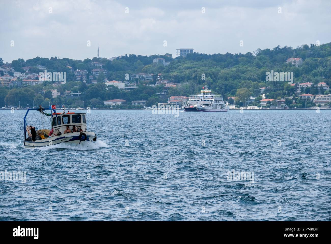 A fishing boat seen in front of a Cityline Ferry in Bosphorus. While ...