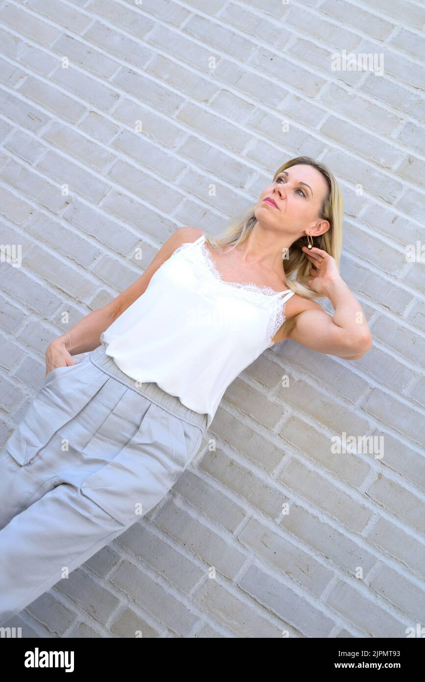 Angled portrait of a stylish middle aged blond woman in summer fashion ...