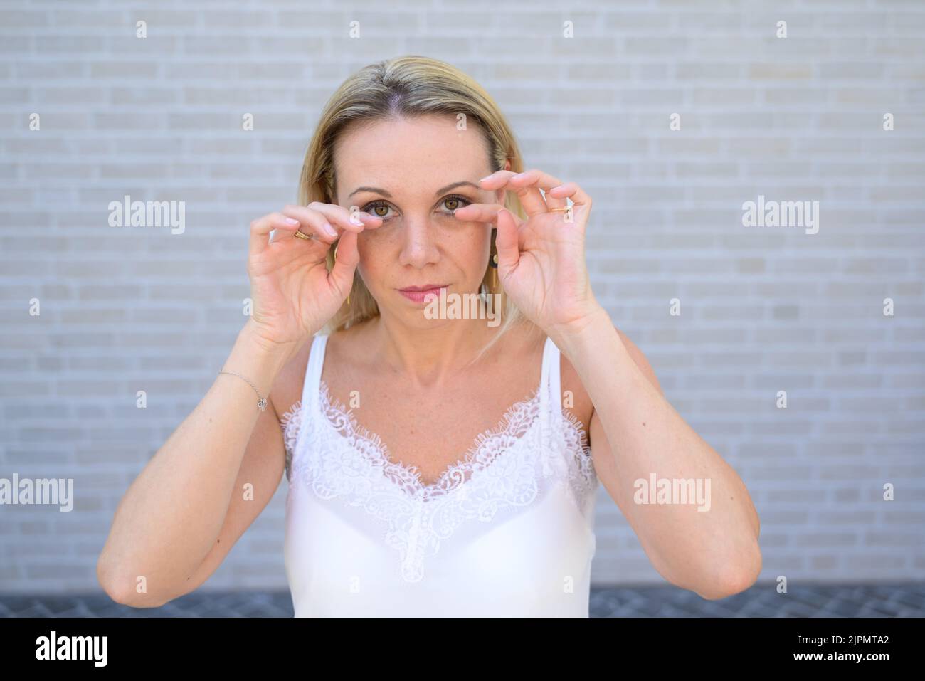 Woman holding her fingers to her eye lashes as she stares intently at ...