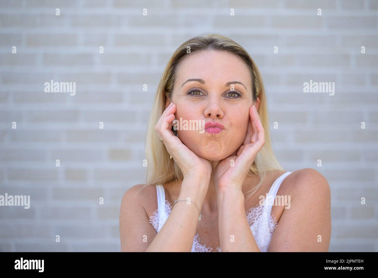 Attractive fun loving woman pursing up her lips for the camera as ...
