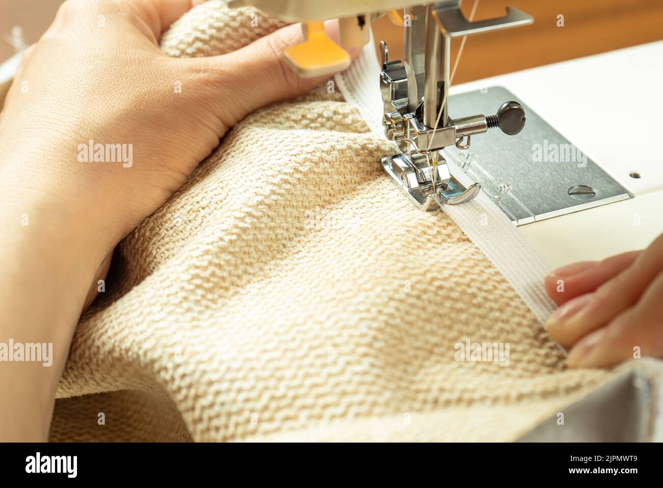 Seamstress hands holding white textile fabric. Female hands stitching ...