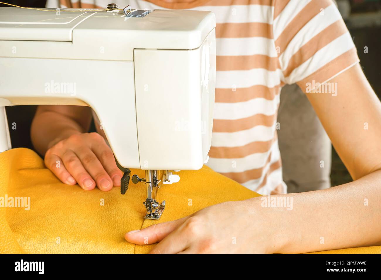 Seamstress female hands holding and stitching yellow textile fabric on ...