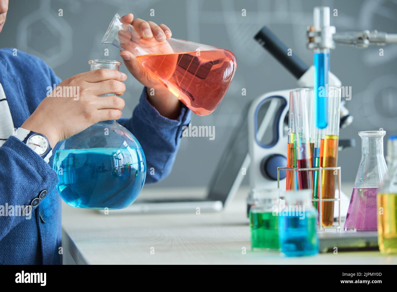 Close-up shot of unrecognizable boy pouring red liquid into other flask ...