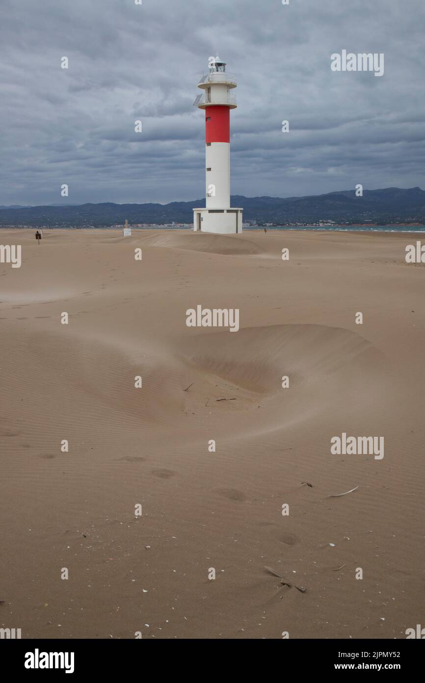 The vertical view of a lighthouse on the sand under the cloudy sky ...