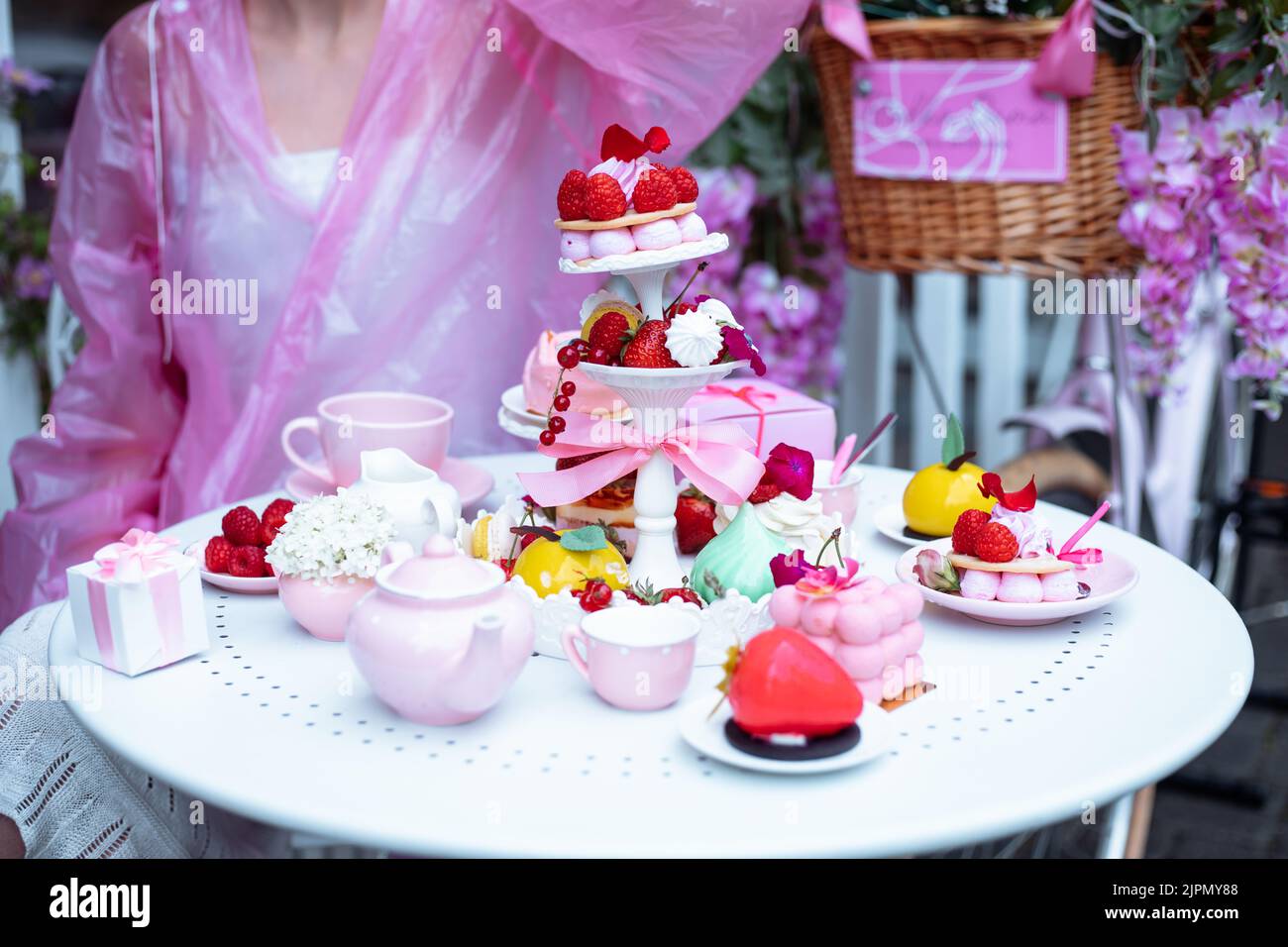Unrecognizable woman in pink raincoat eat sweet berry desserts ...