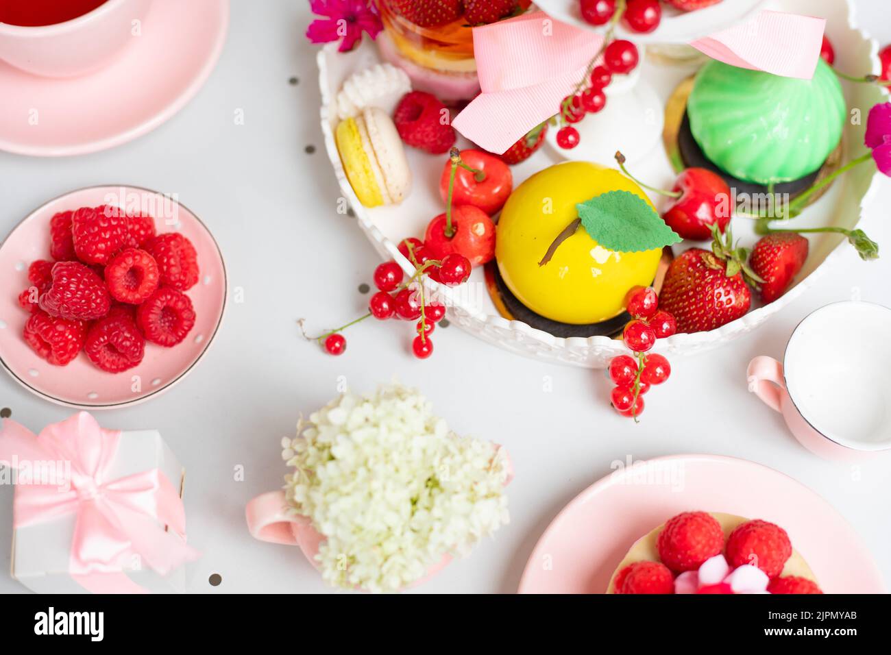 Pink and white sugar treats and berry, fruit desserts on cake stand ...