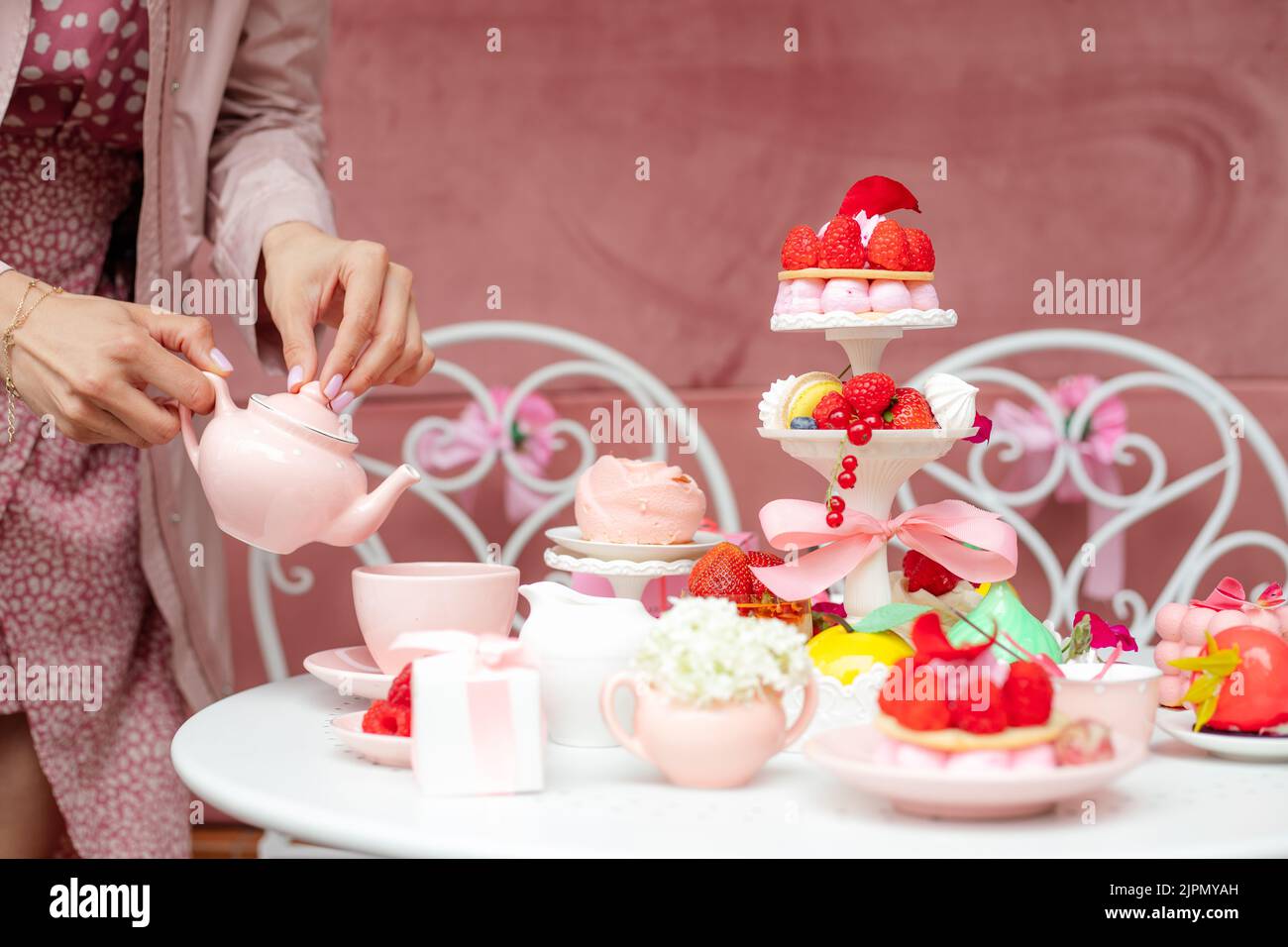 Unrecognizable woman hands pouring tea in cup on table in candy shop or ...