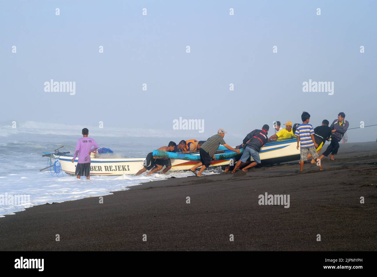 A view of some people helping pull fishing boats to the beach Stock ...